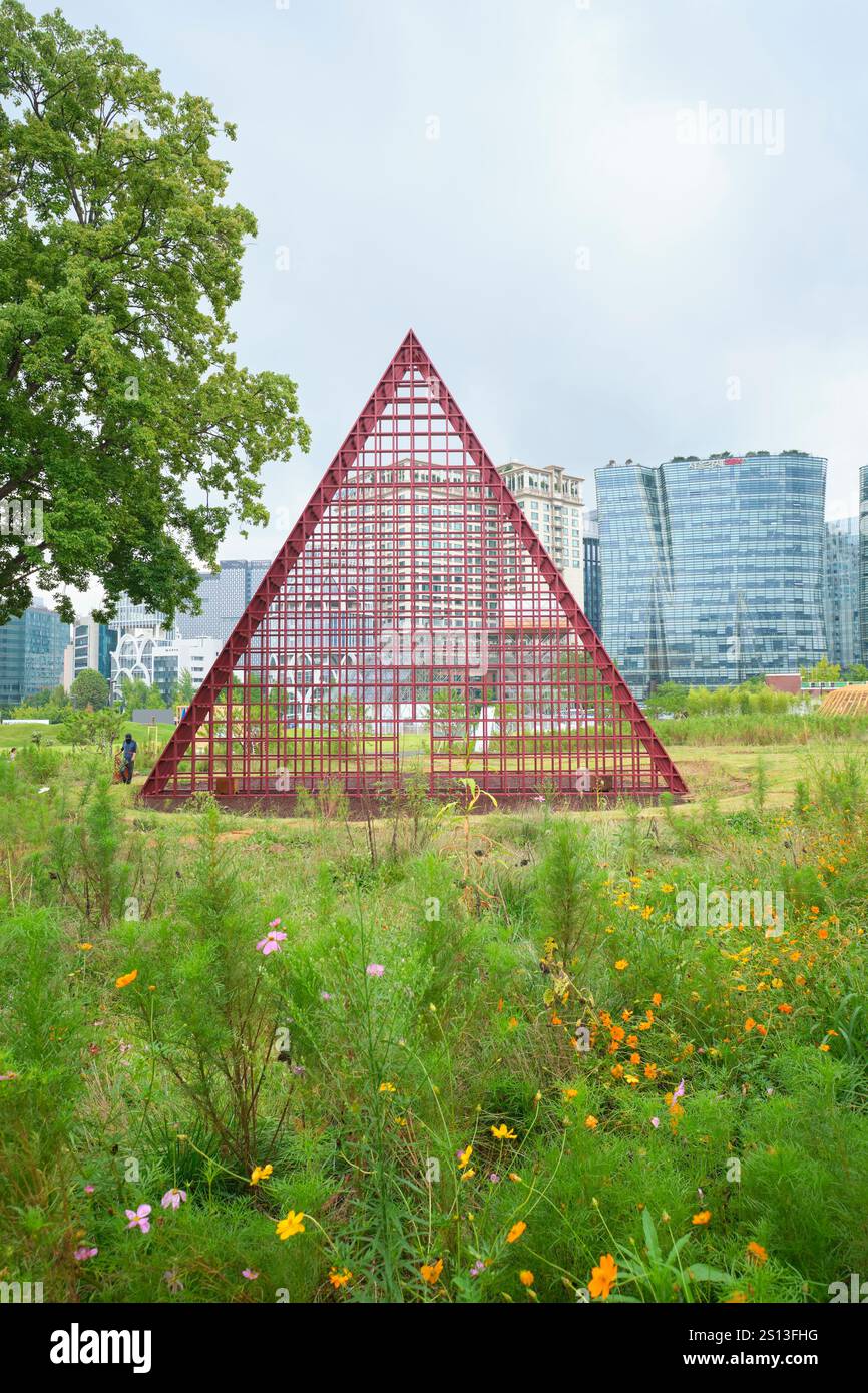 A large, red, steel triangle sculpture, statue in the park. At the ...