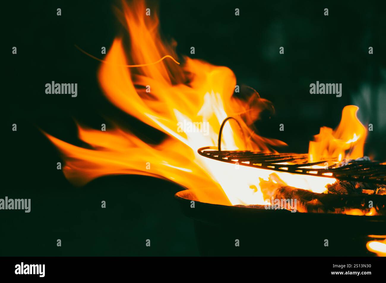 The fire's burning in the brazier. BBQ outdoors at night. Dangerous hot ...