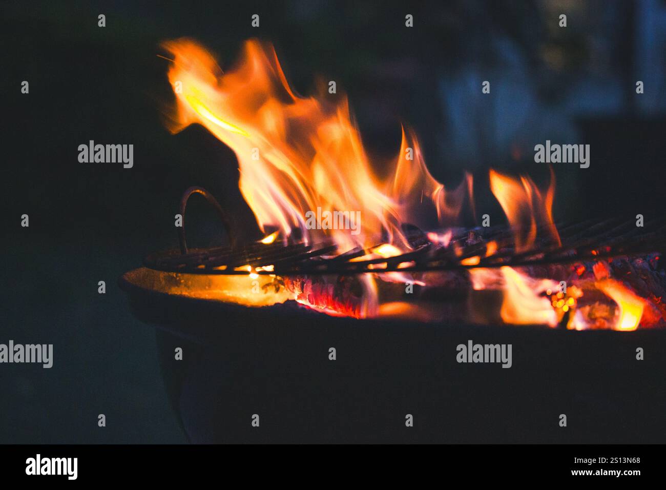 The fire's burning in the brazier. BBQ outdoors at night. Dangerous hot ...