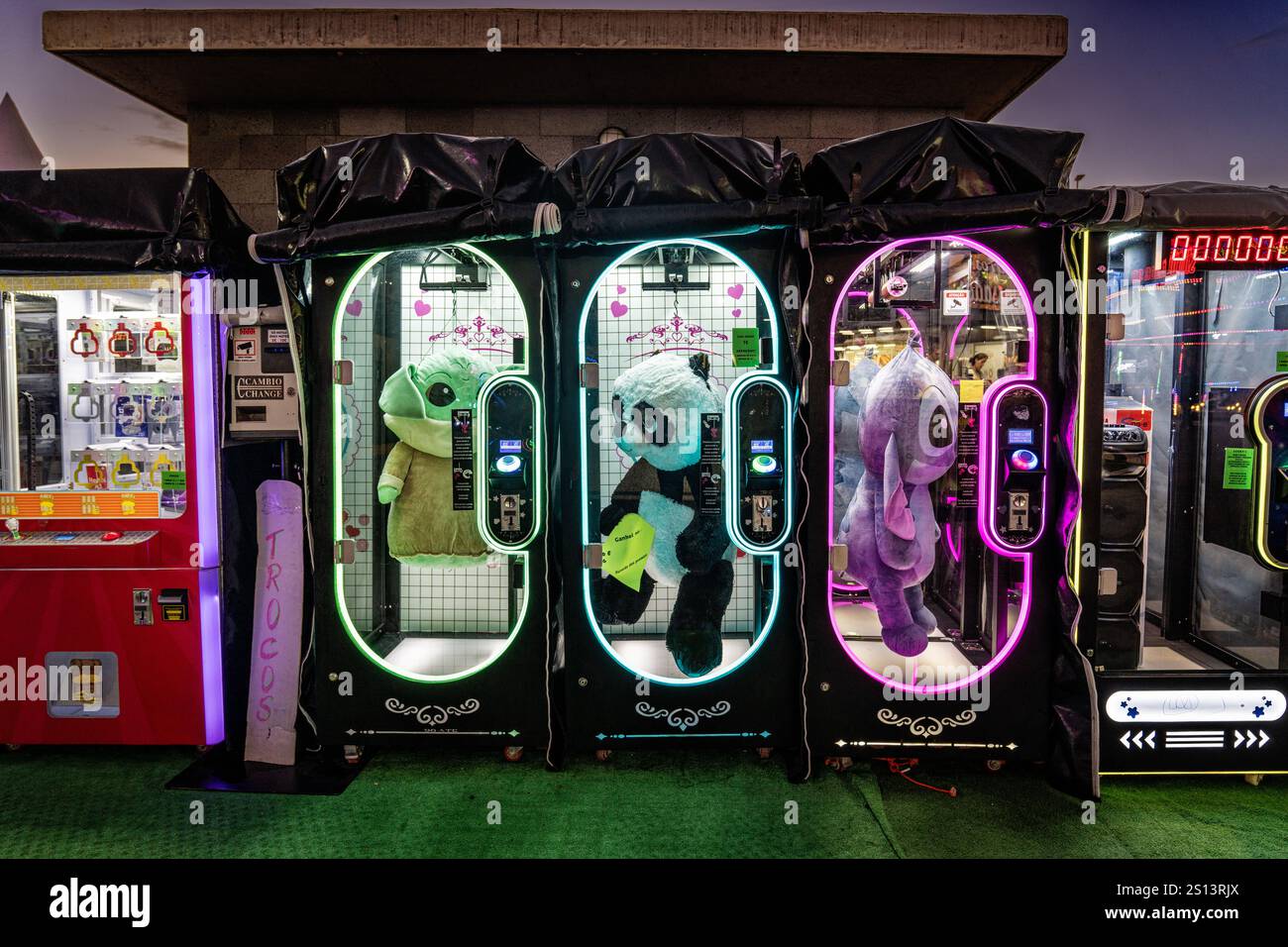 Colorful claw machines featuring plush animal toys and neon lights ...
