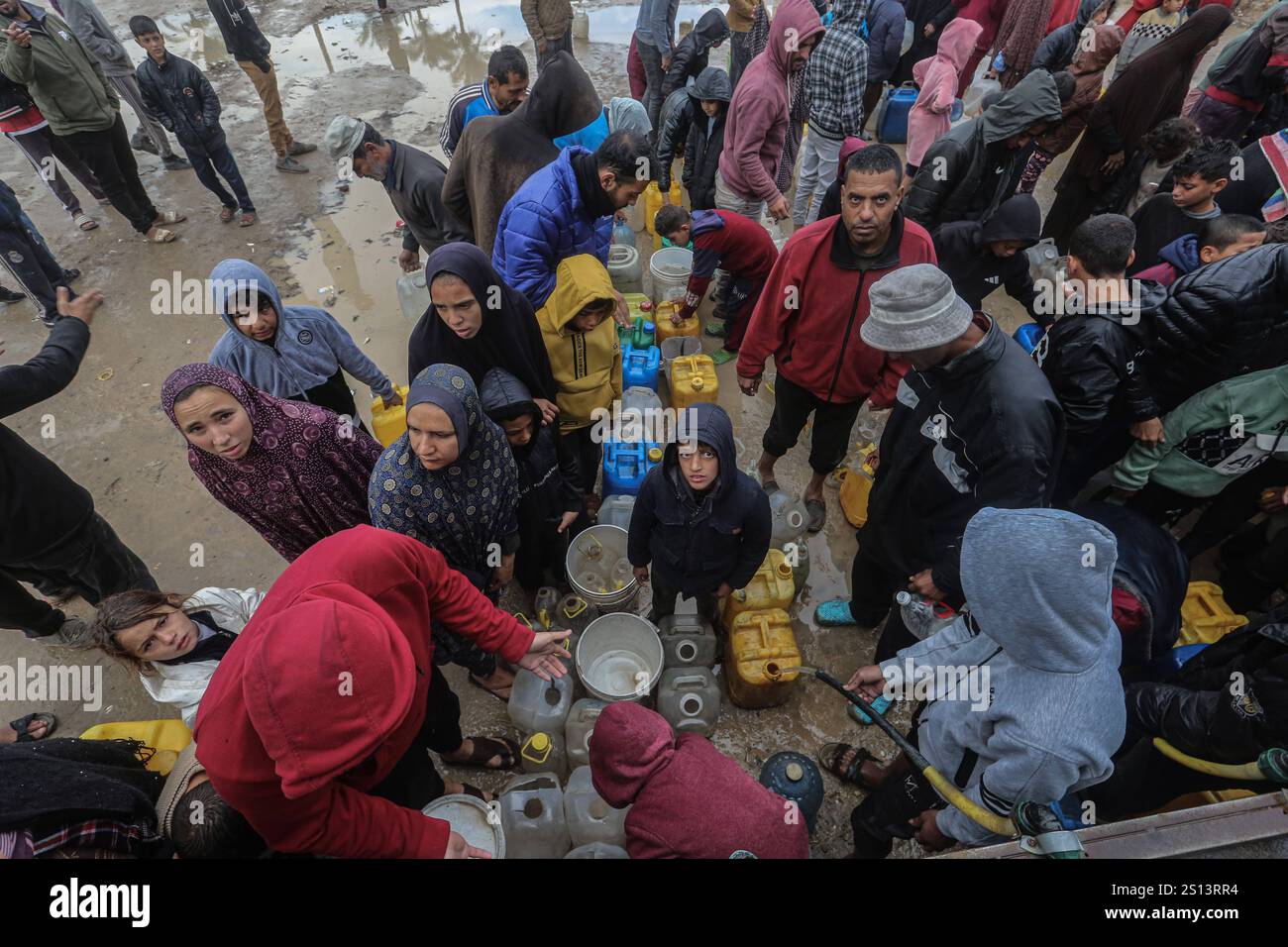 Palestinians, including children, line up to collect drinking water ...