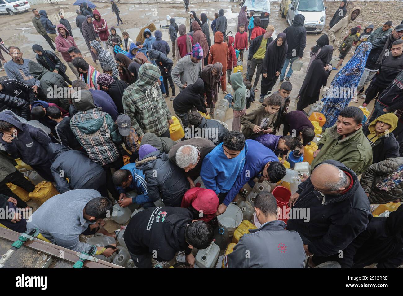 Palestinians, including children, line up to collect drinking water ...