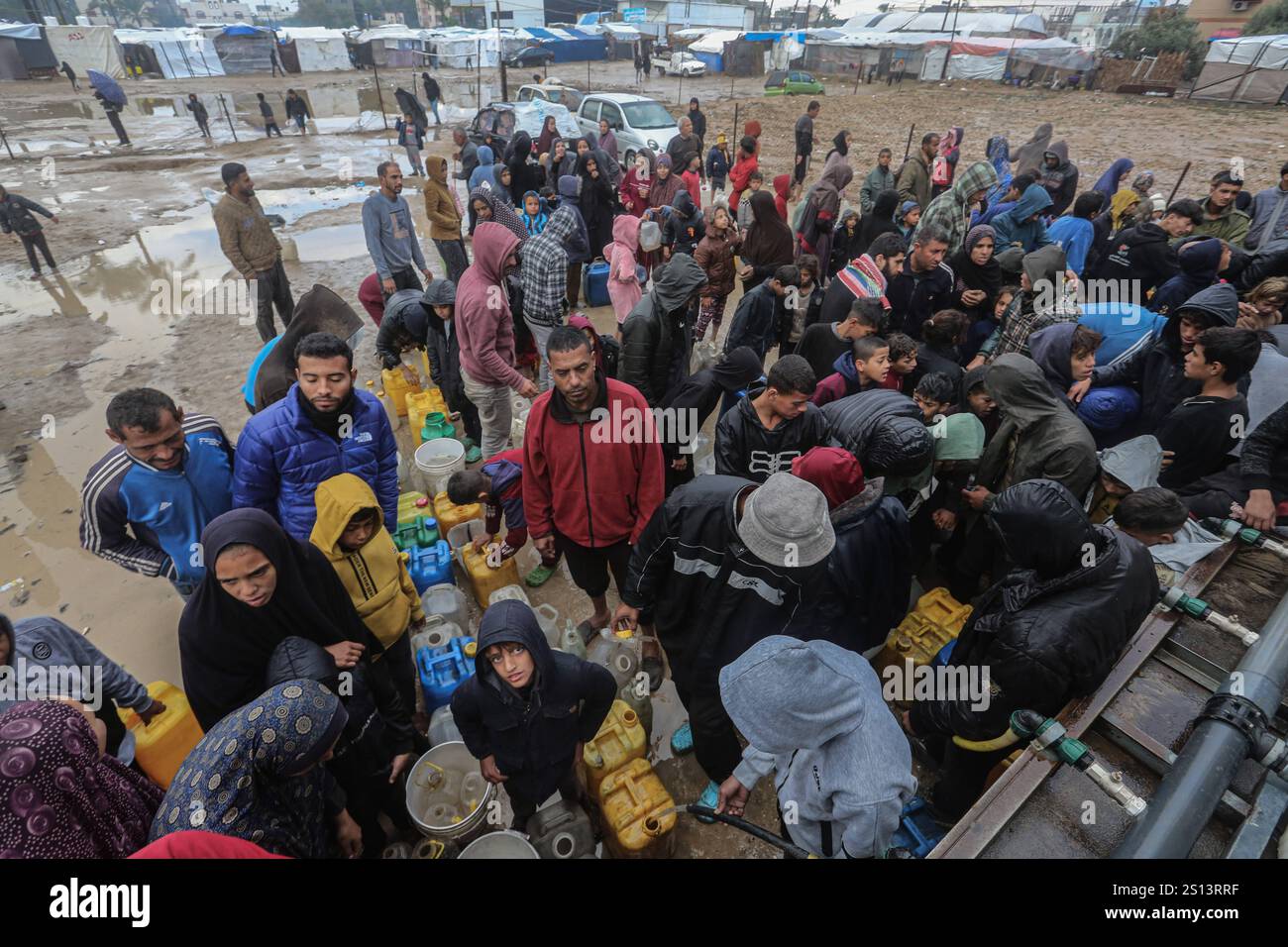 Palestinians, including children, line up to collect drinking water ...