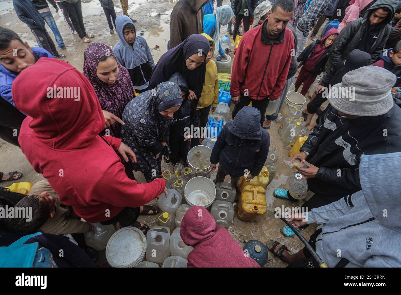 Palestinians, including children, line up to collect drinking water ...