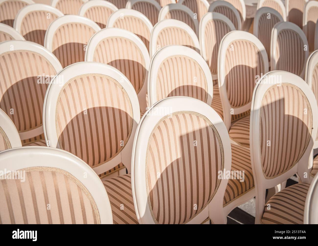 Rows of baroque cream-colored chairs. Lots of chairs with striped beige ...