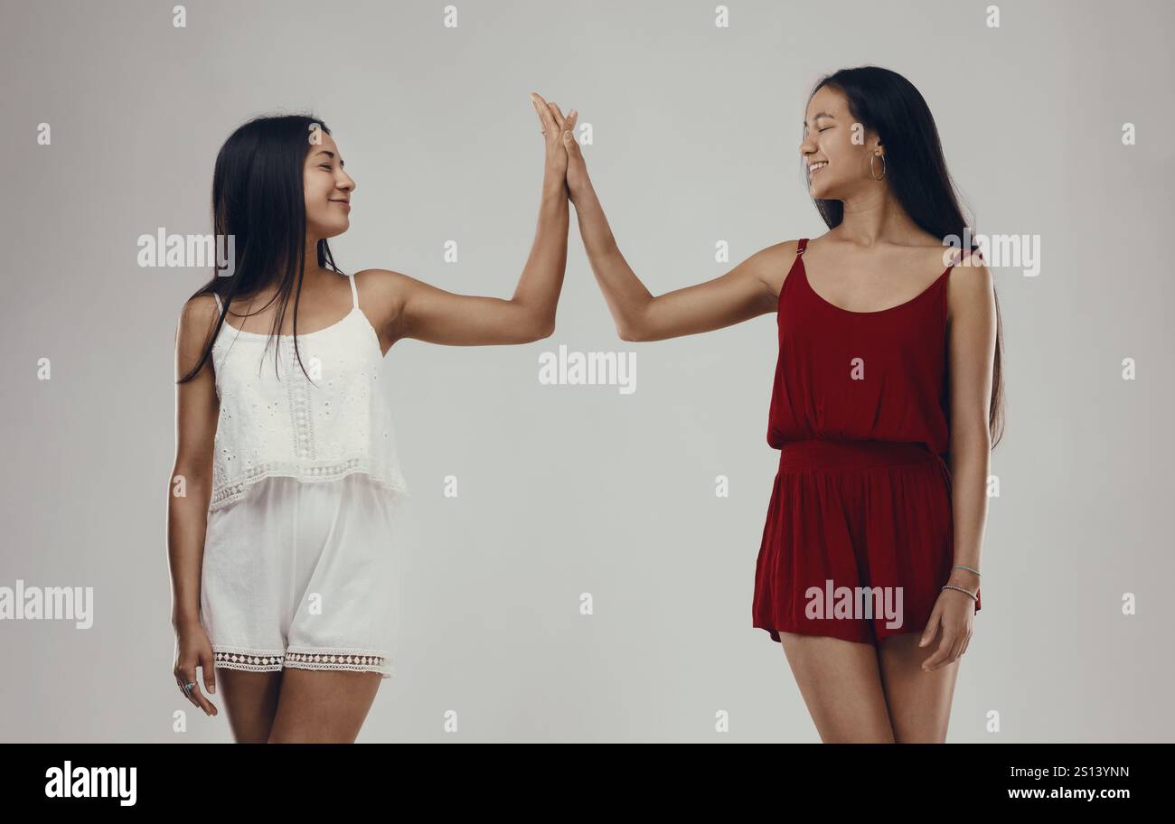 Two joyful young adult filipino women sharing a high five, celebrating ...