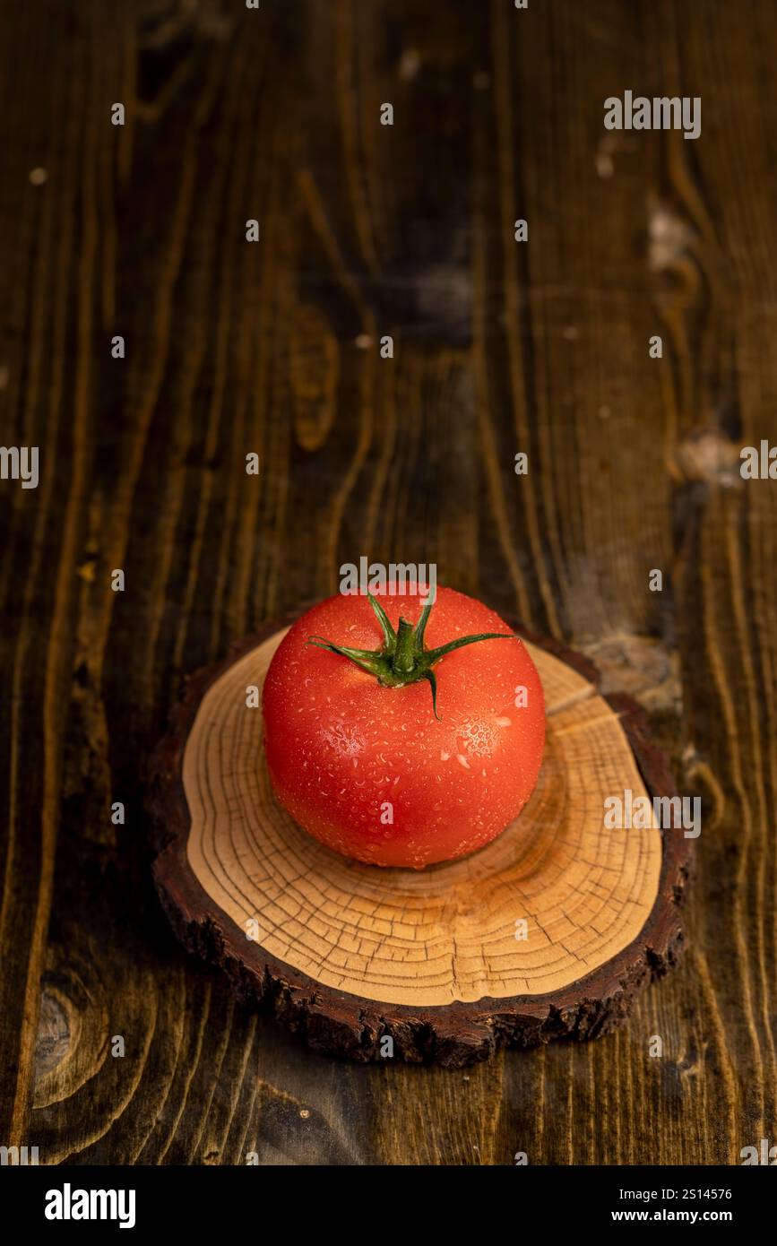 one wet ripe red tomato on the table, fresh soft tomatoes in drops of ...