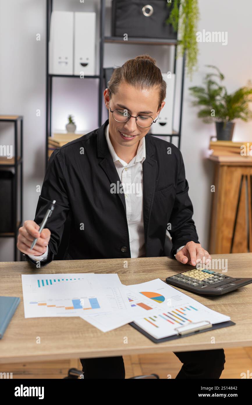 Focused young office worker working with schedules and financial ...