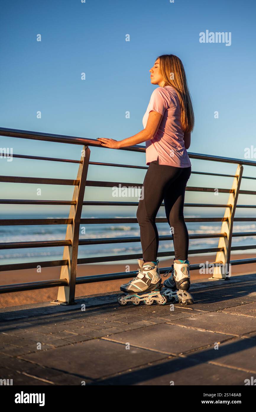 vertical Woman in athletic attire enjoys inline skating along a seaside promenade, basking in ...