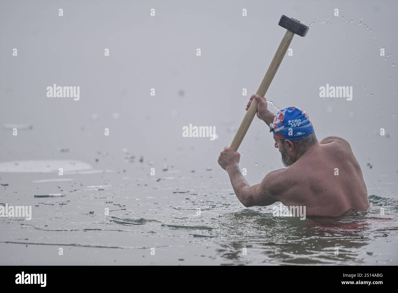 Swimmer breaking ice in a frozen lake during a traditional swimming on ...
