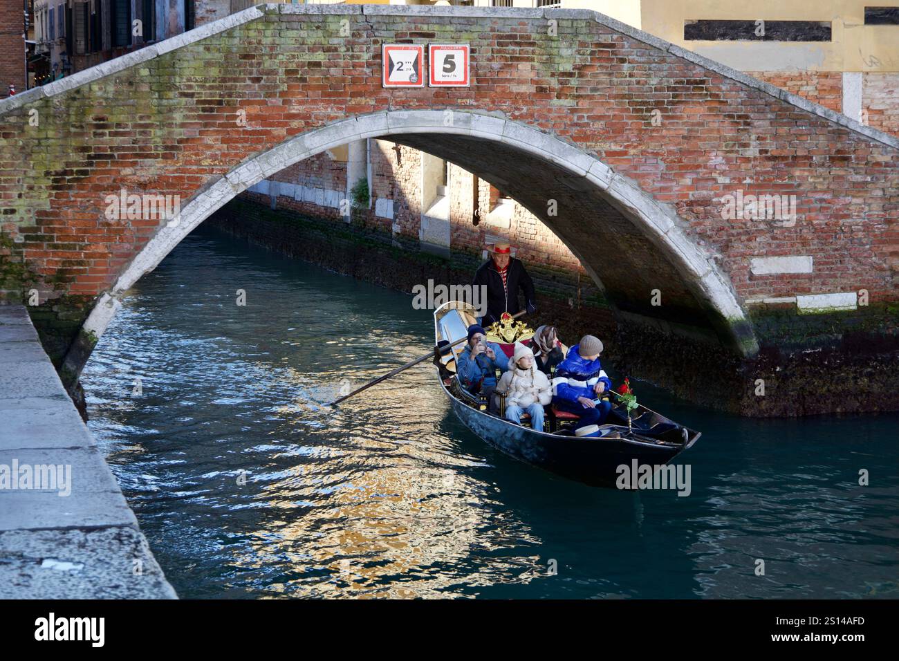 Venice, Italy. December 26, 2024. A gondola crossing a narrow canal in ...