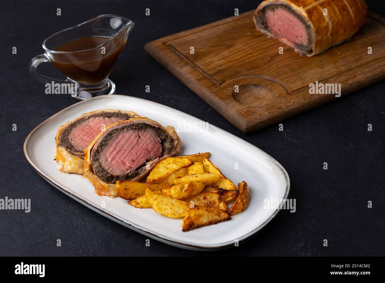 Beef Wellington with baked potato slice and demi-glace sauce ...