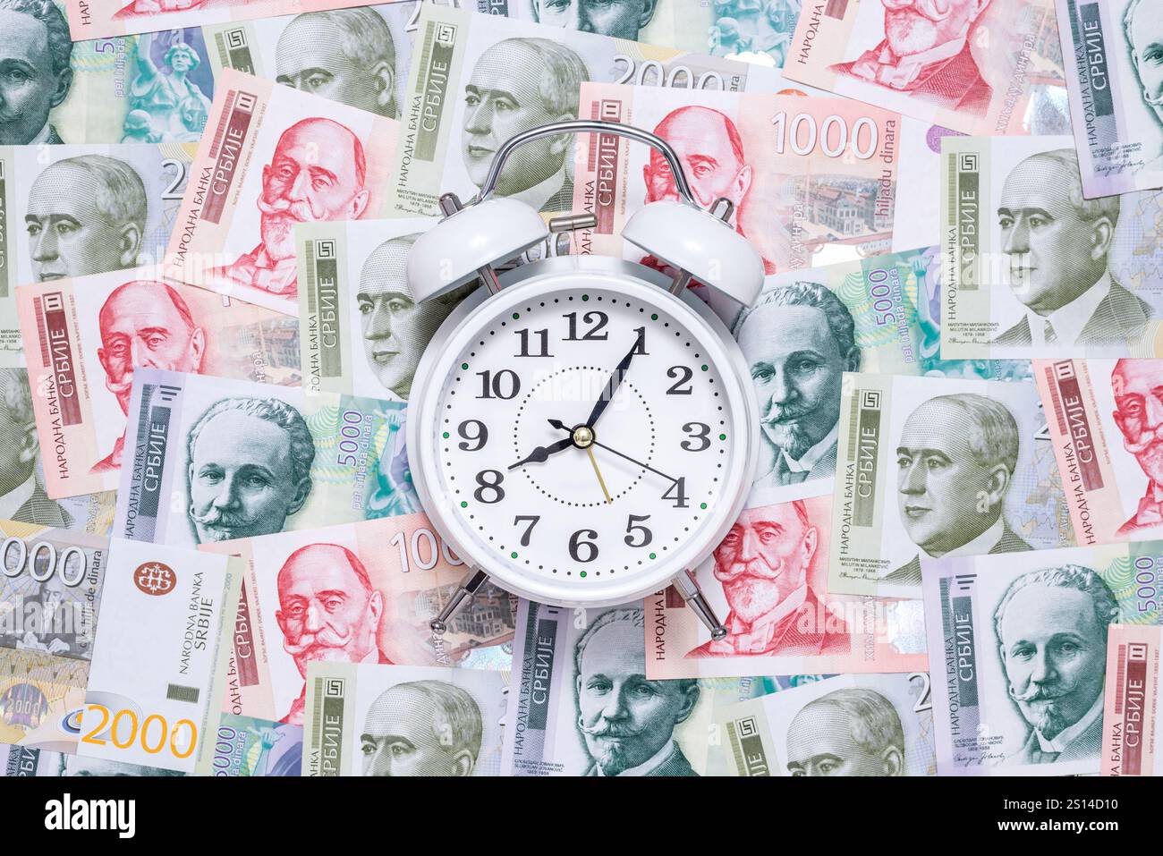 White retro alarm clock and heap of Serbian dinar paper currency, 1000 ...
