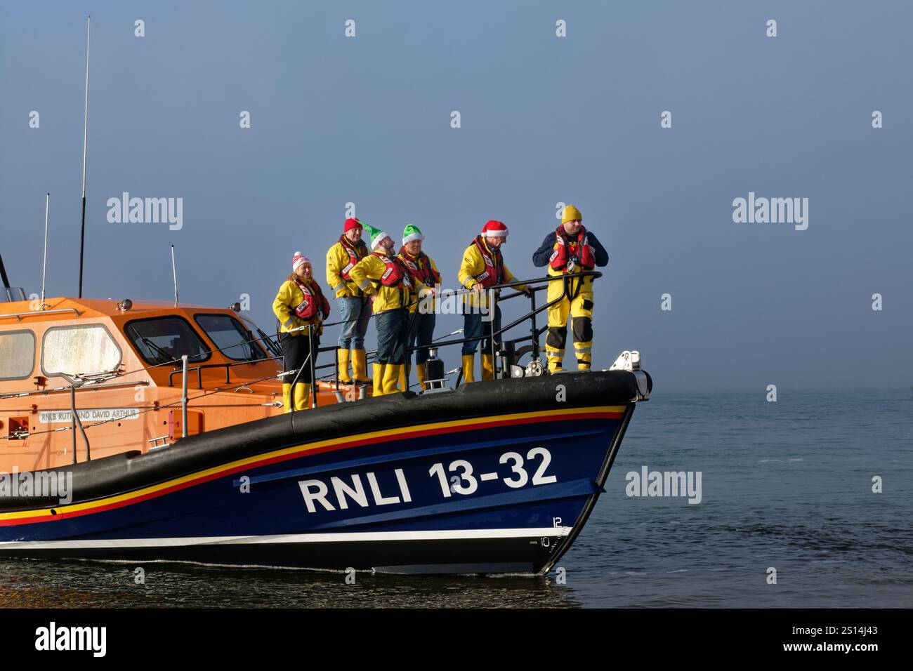 Lifeboat with crew in festive hats moored just off Exmouth Beach ahead ...