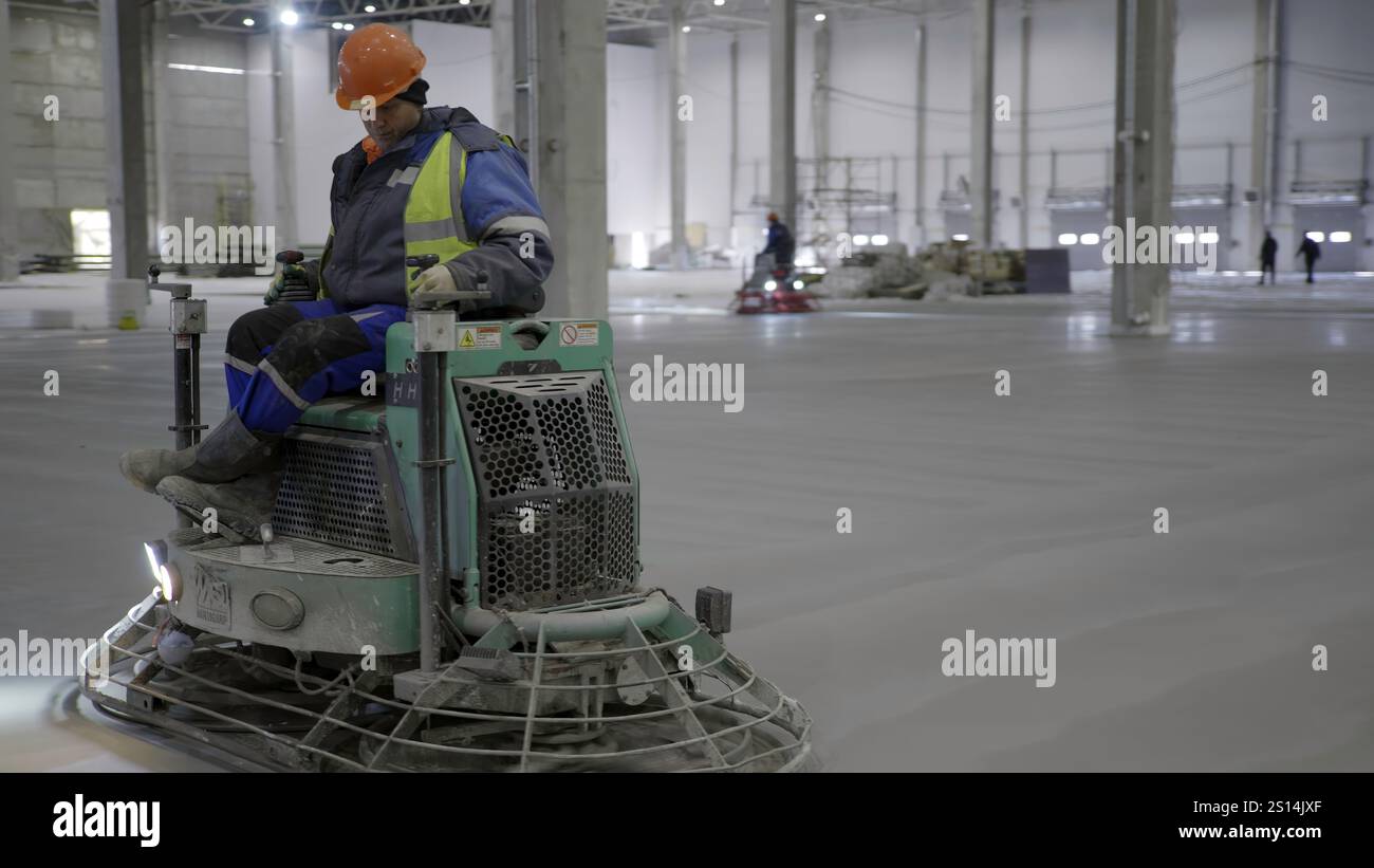 A Worker Who Operates a Concrete Finishing Machine Inside a Warehouse ...
