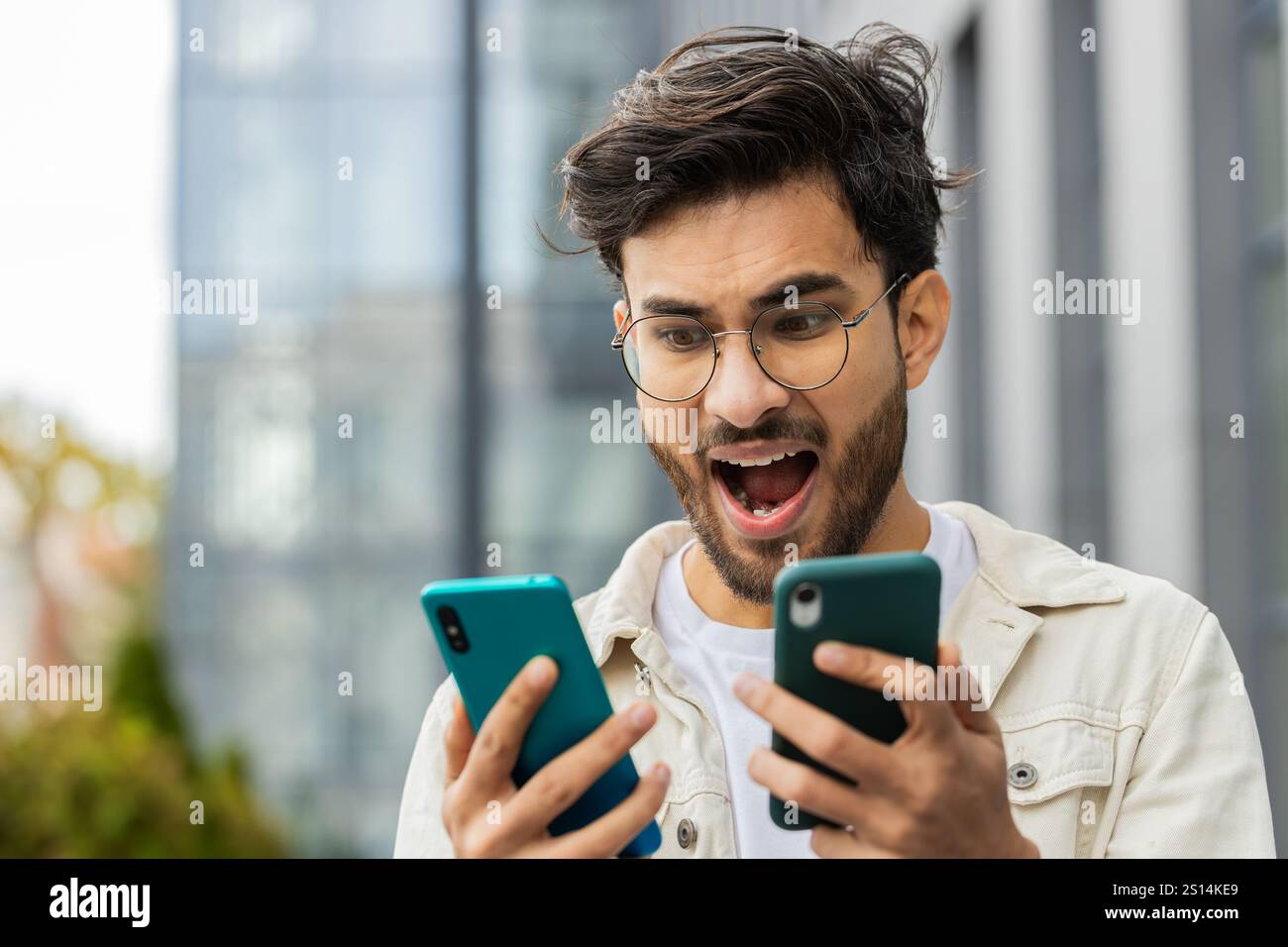 Irritated nervous stressed Indian man talking screaming on two mobile ...