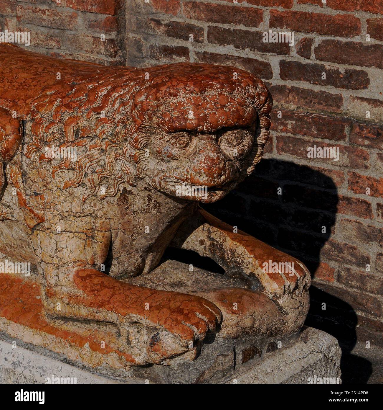 A crouching medieval lion, sculpted in Romanesque style, turns its ...
