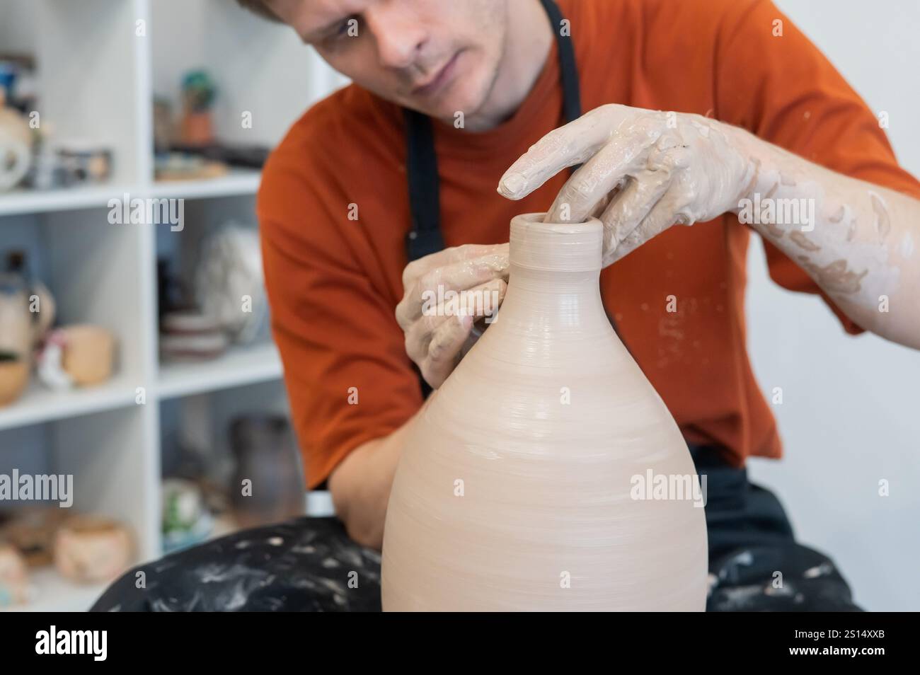 A potter works on a potter's wheel to smooth the surface of a vase ...