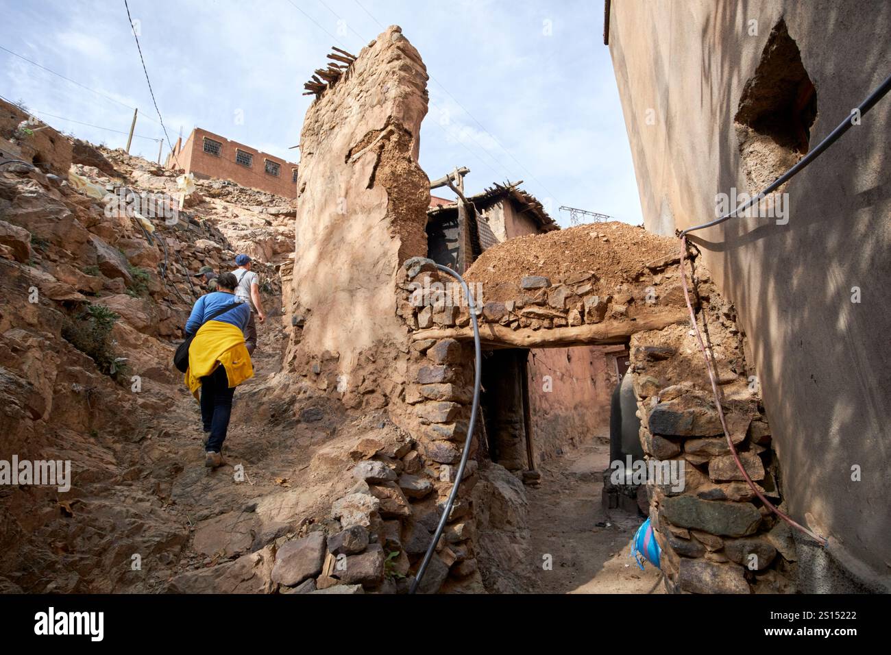 tourists walking up tracks between berber houses as part of a guided ...