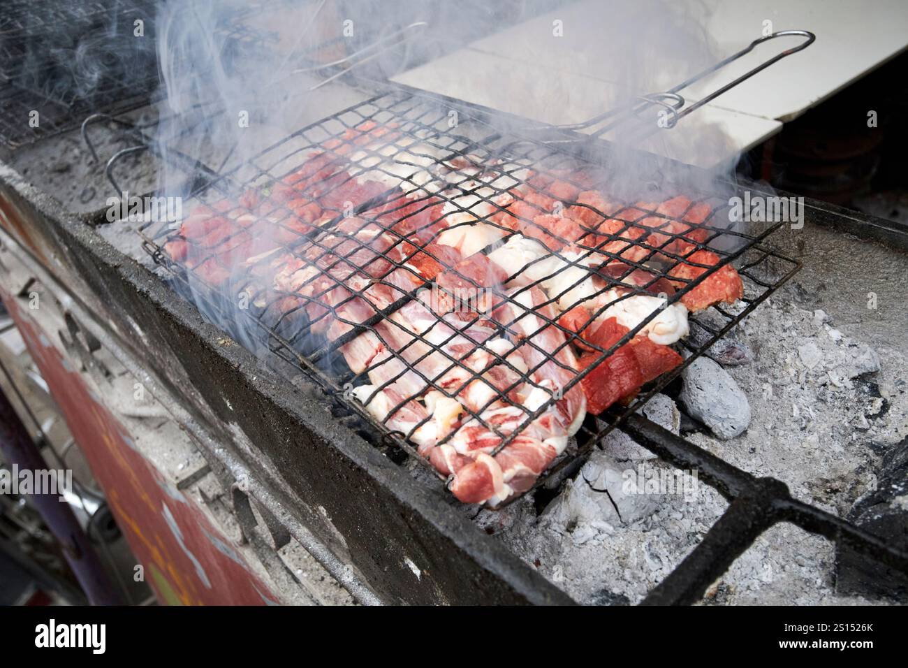 cooking meat by the roadside in a cafe over hot charcoal open air ...