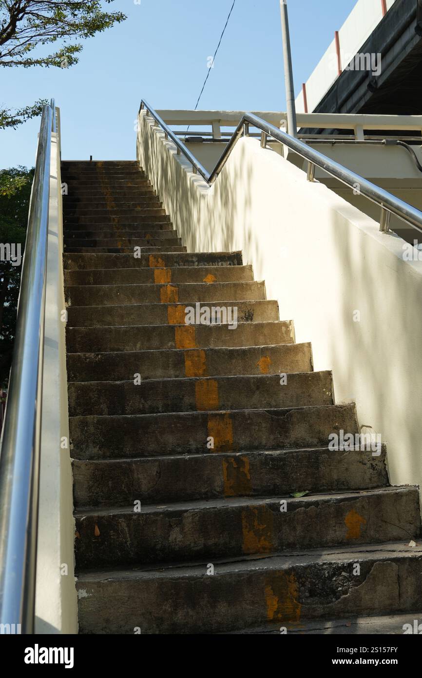 Concrete stairs with handrail leading up the slope against the ...