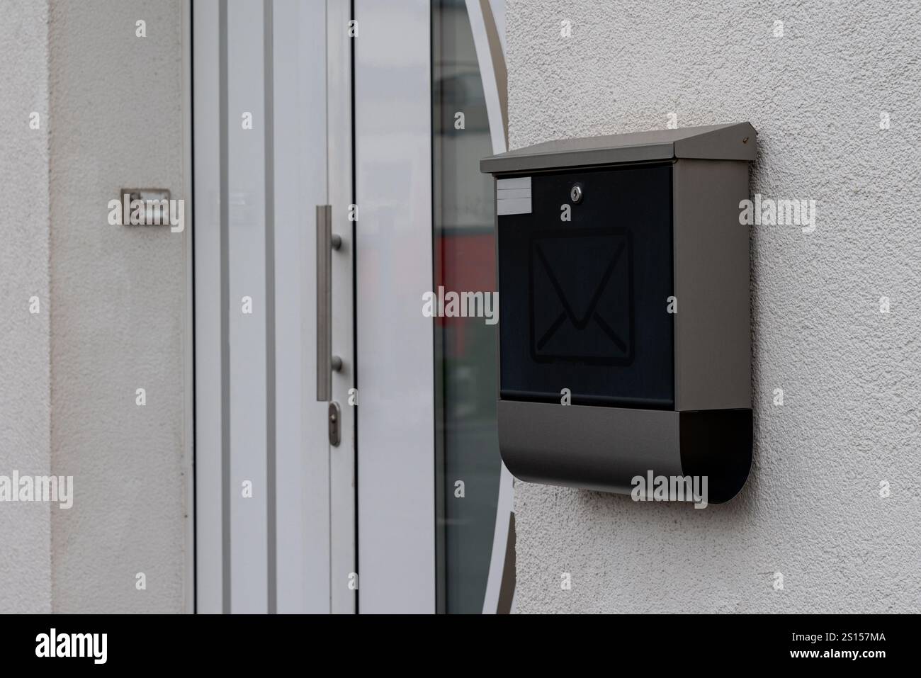 A sleek black mail box is mounted to the wall beside a contemporary ...