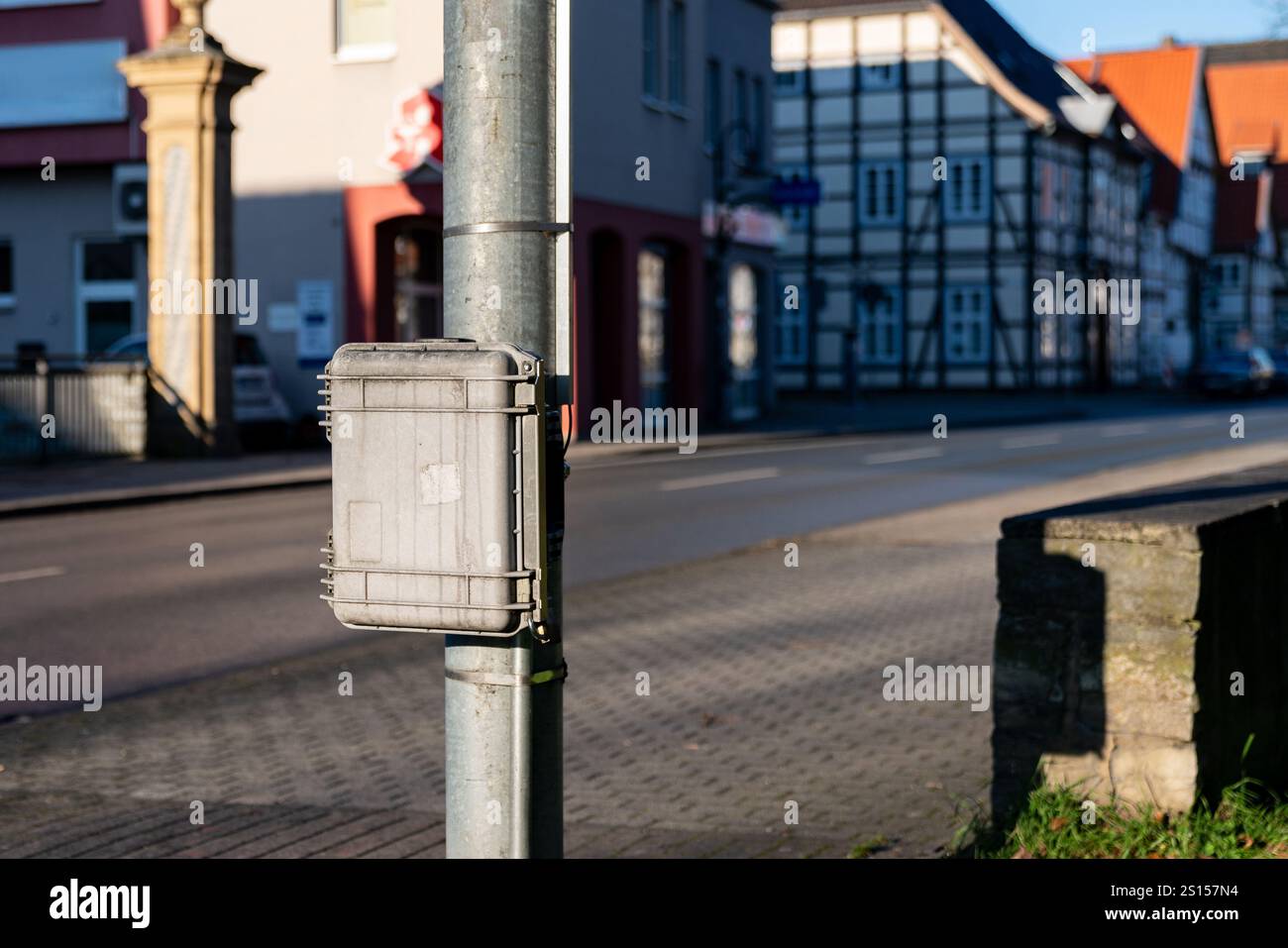 A utility box is attached to a pole on a quiet urban street. The ...