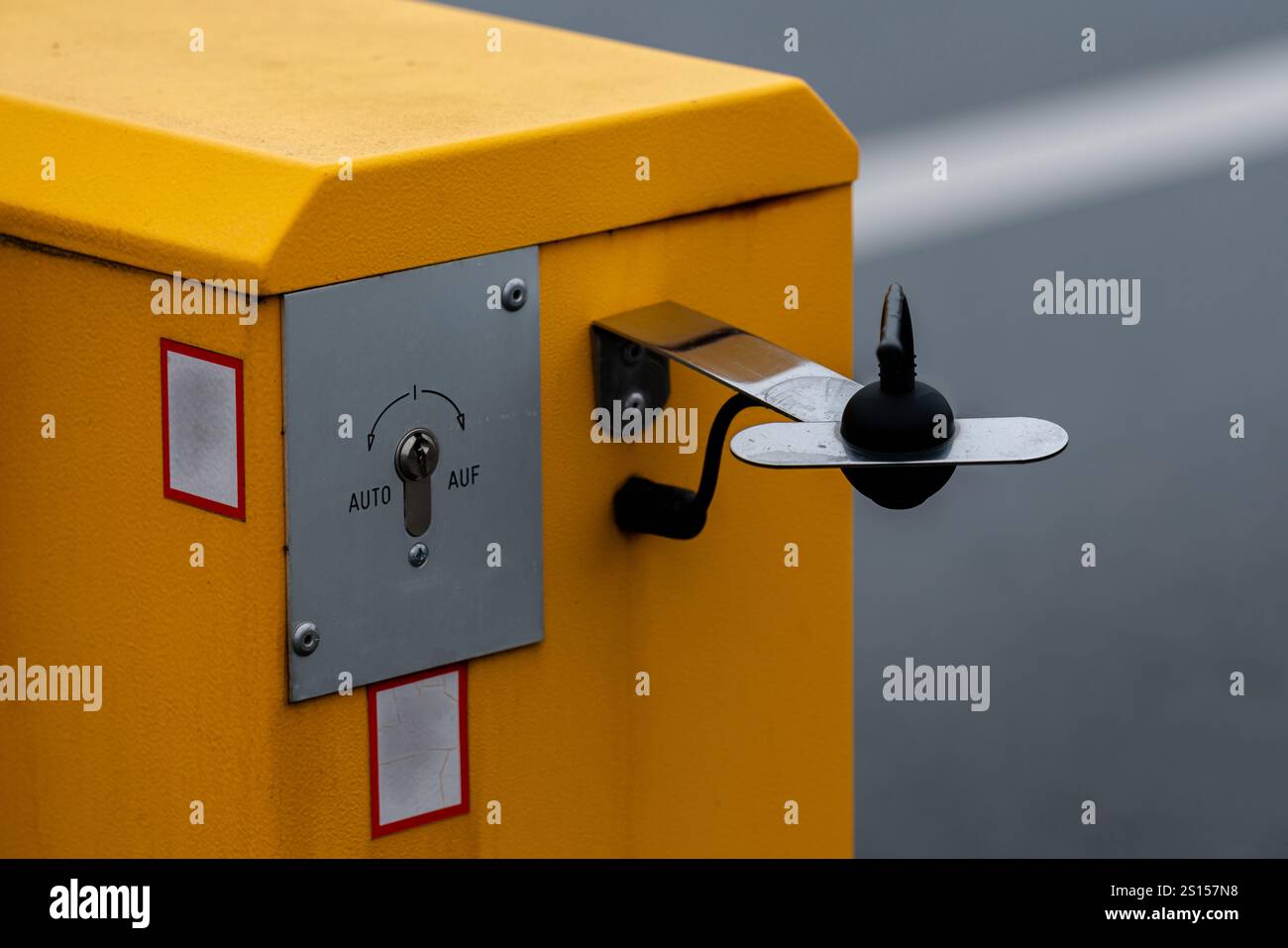 This yellow barrier control device is installed in a parking area. It ...