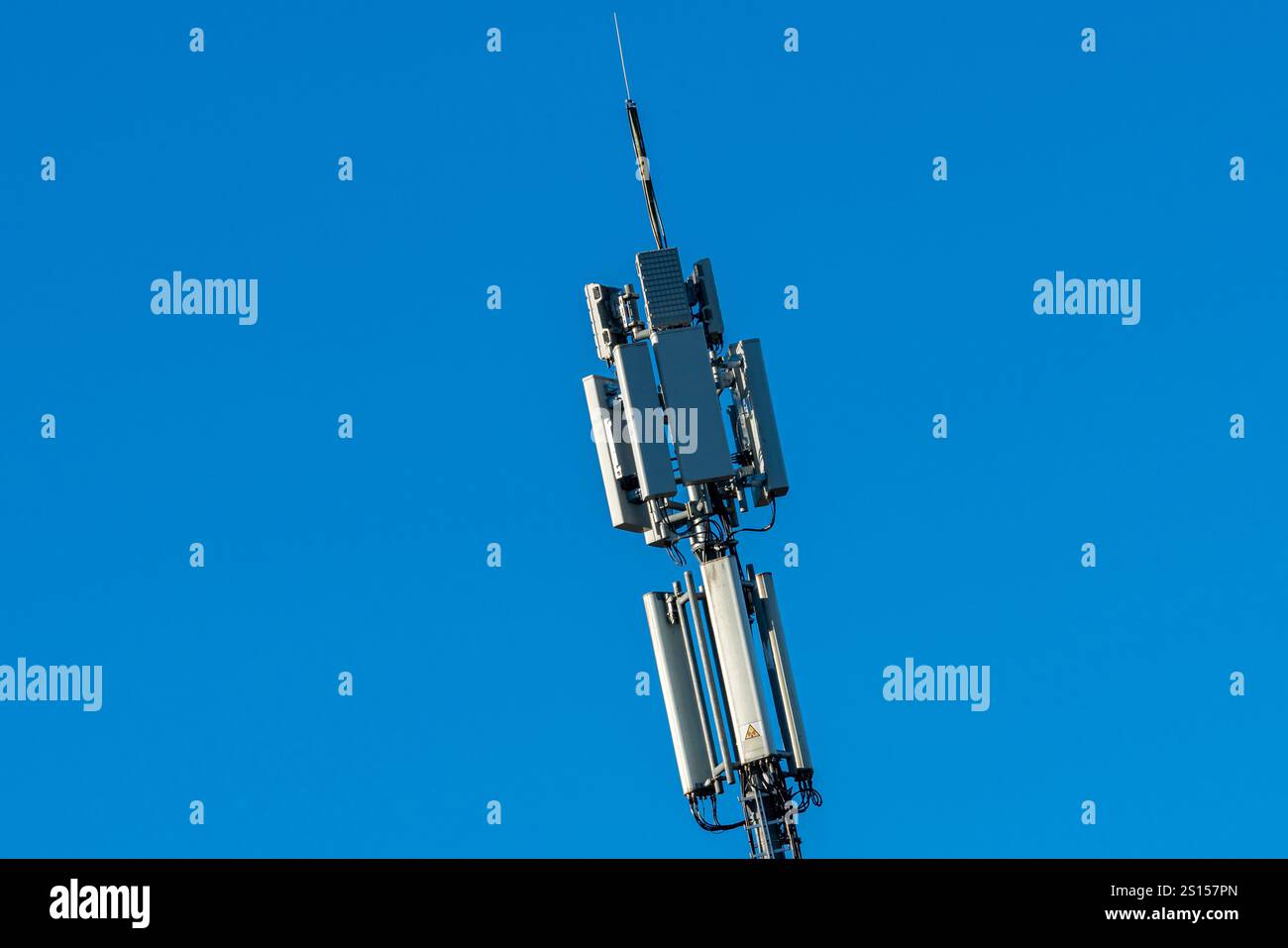 A tall communication tower stands prominently against a clear blue sky ...