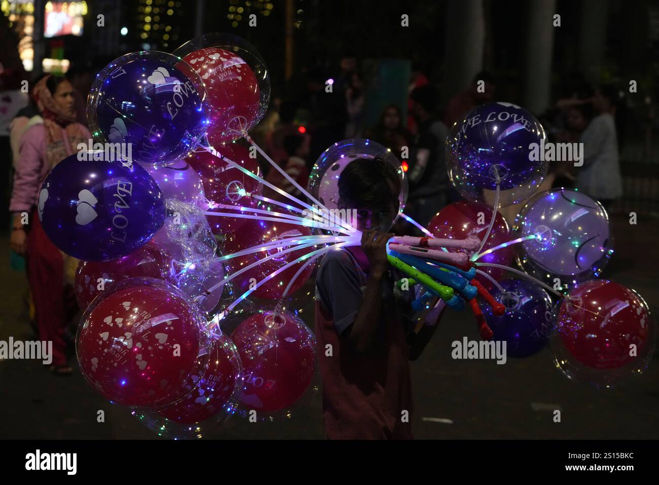 A boy sell balloons as people throng at C G road to celebrate the New ...