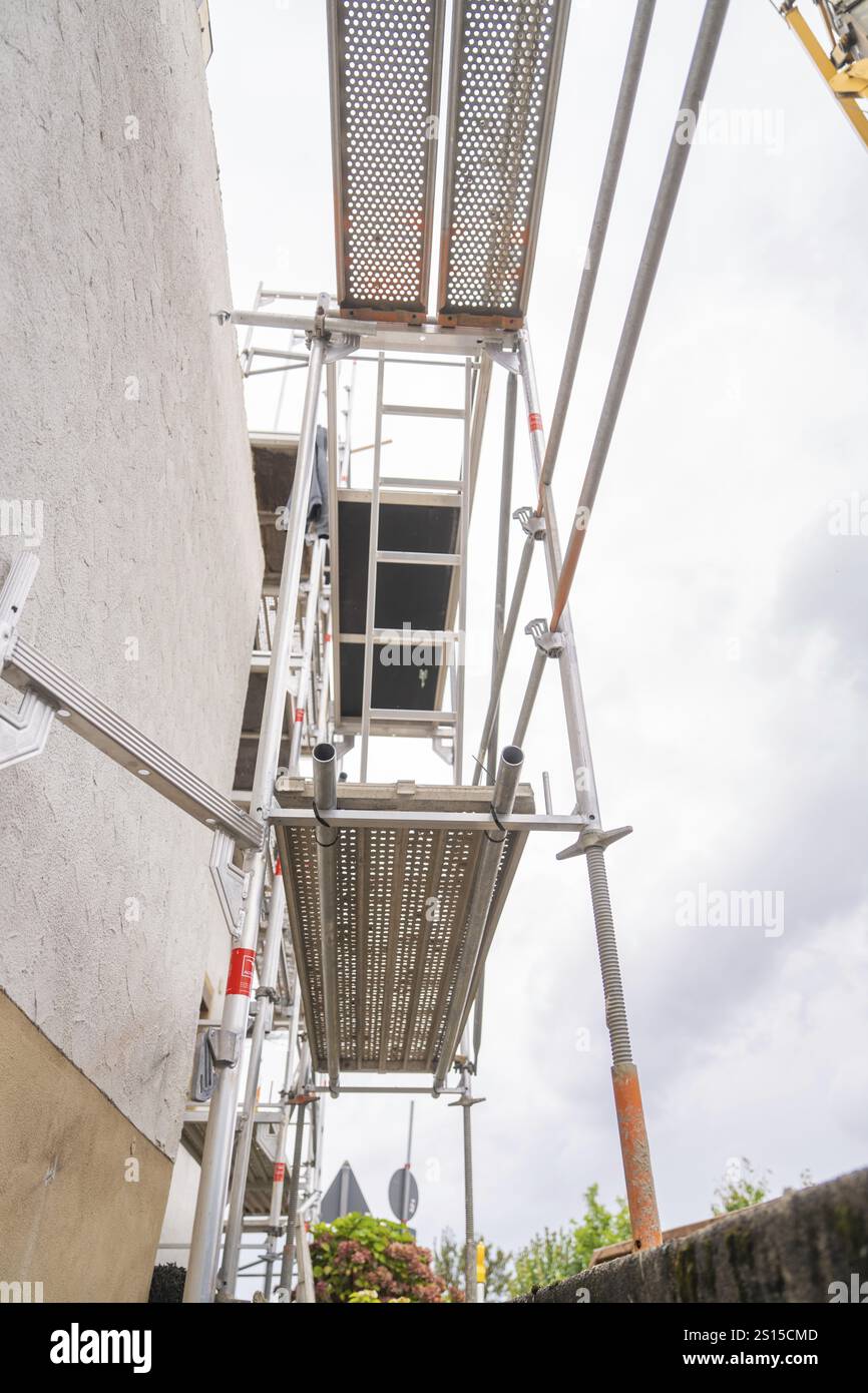 View from below of scaffolding next to a building under a cloudy sky ...