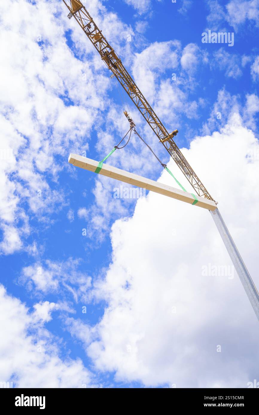 A long beam is lifted by a crane against a clear sky Stock Photo - Alamy