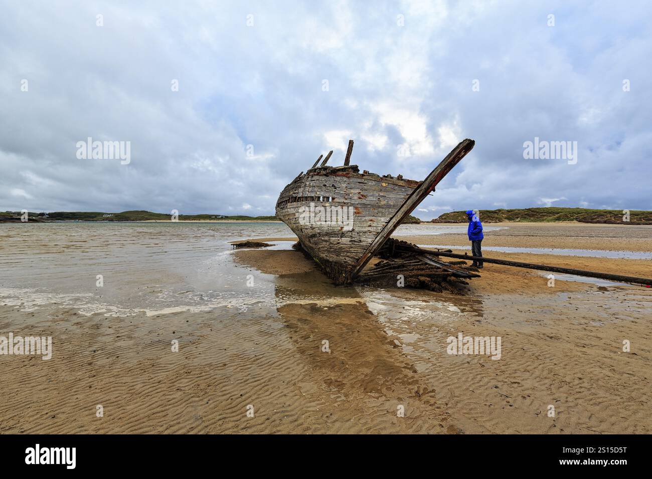 Wooden shipwreck Eddie's Boat, tourist on windy sandy beach, low tide ...