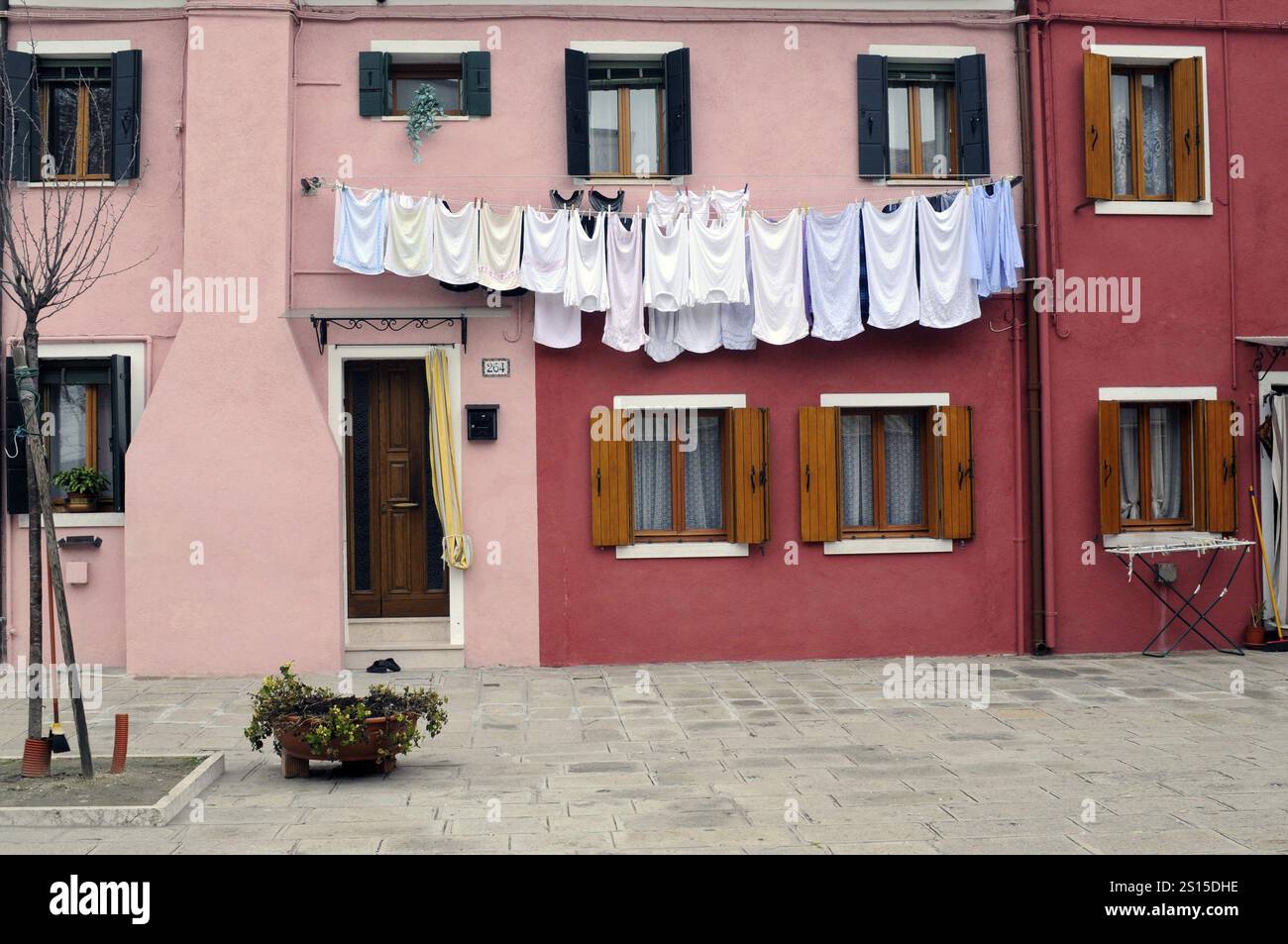 Clean laundry hanging in front of a pink house facade with several windows, Burano, Burano ...