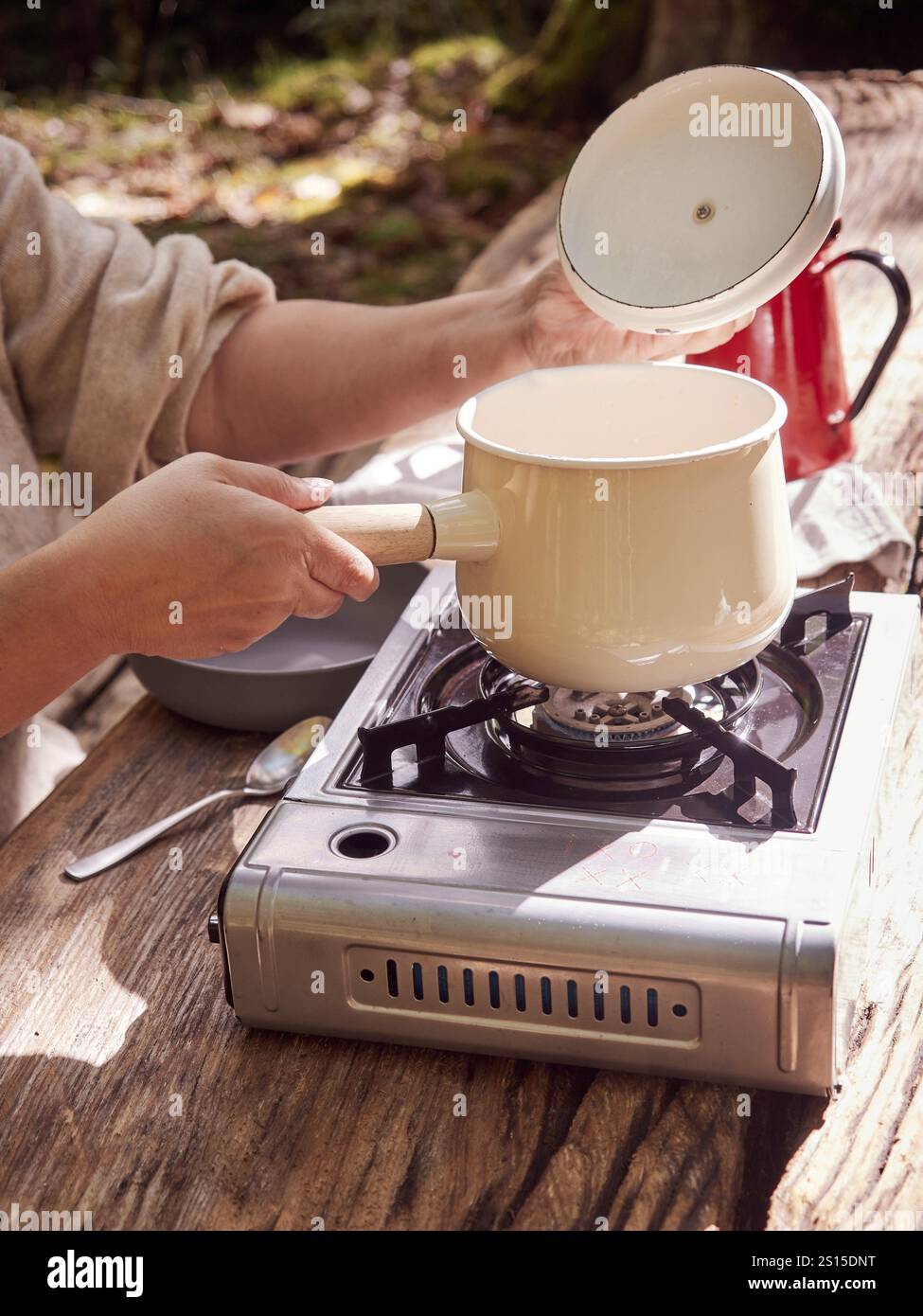 Hand opening the lid of a pot placed on a portable gas stove on a ...