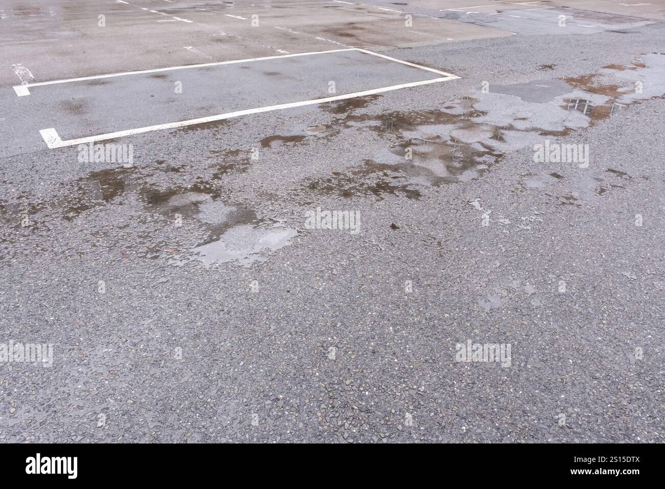 Wet parking lot with puddles reflecting a cloudy sky after a rain ...