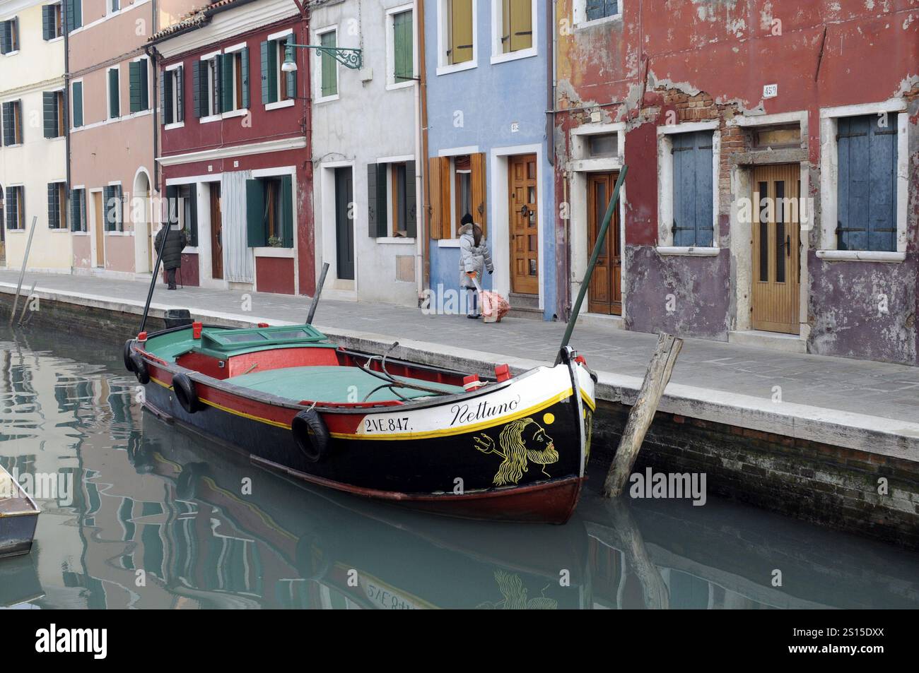 A traditional boat floats peacefully on a city canal, surrounded by ...