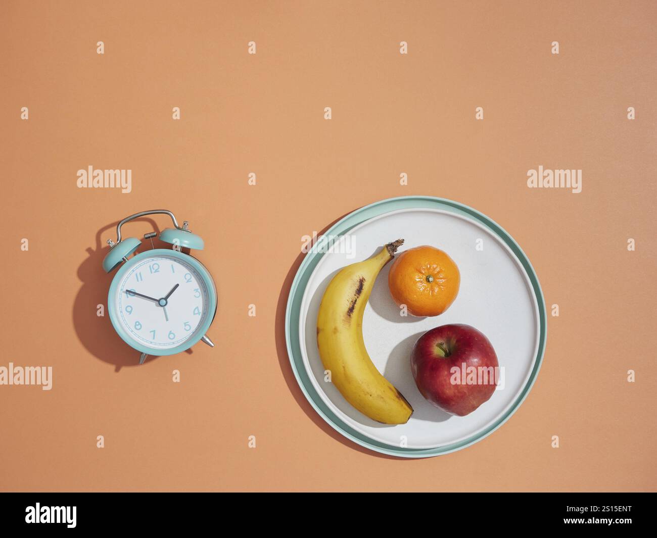 Mealtime, alarm clock and fruits in a plate. Healthy eating concept ...