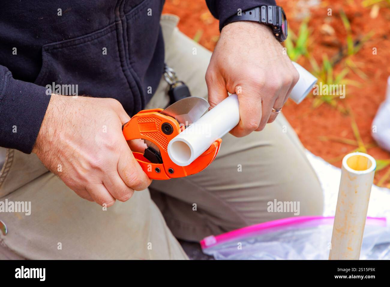 Worker uses hand tool to cut PVC pipe while working at home improvement ...