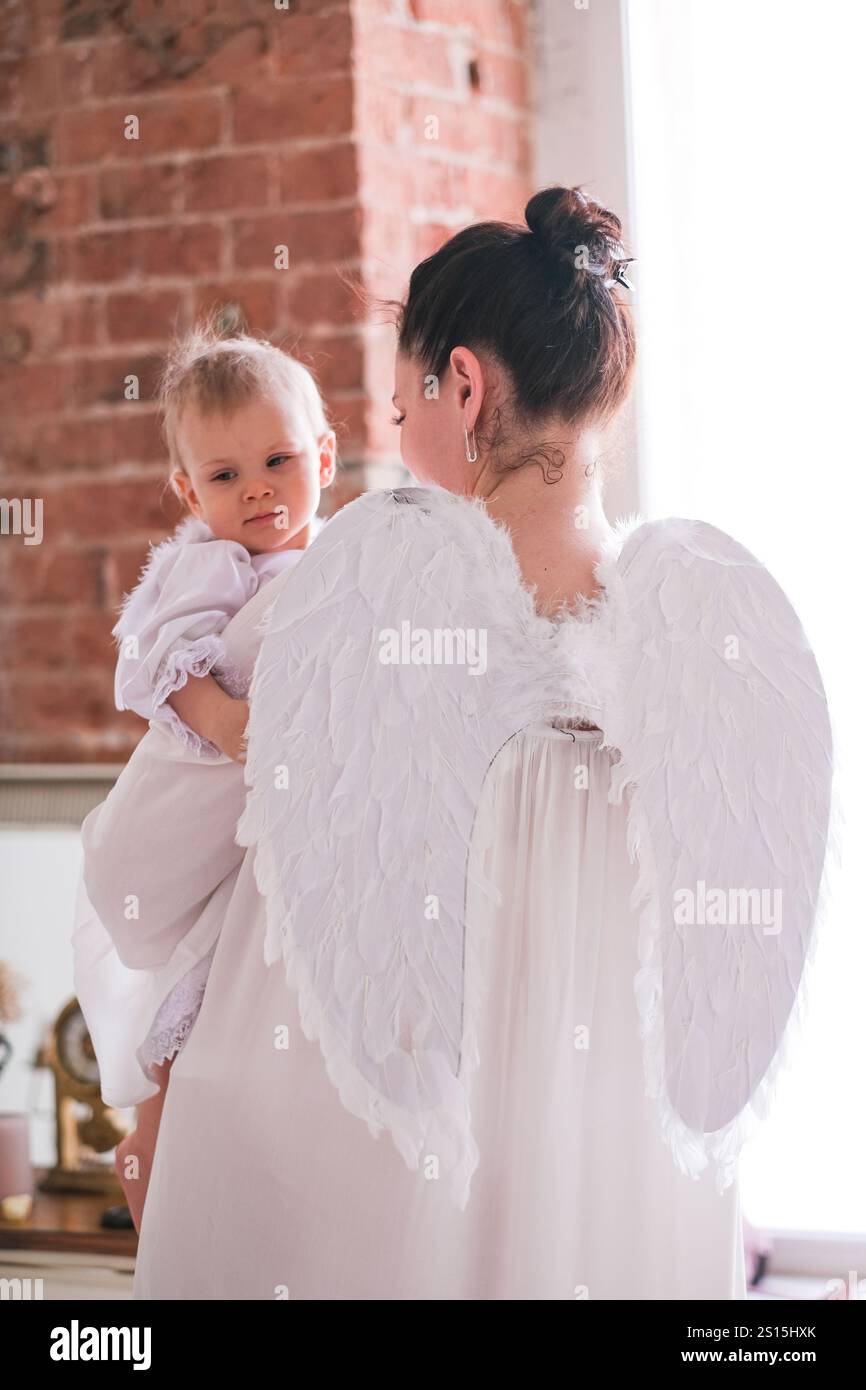 Beautiful mother and her toddler daughter wearing angel costumes. High ...