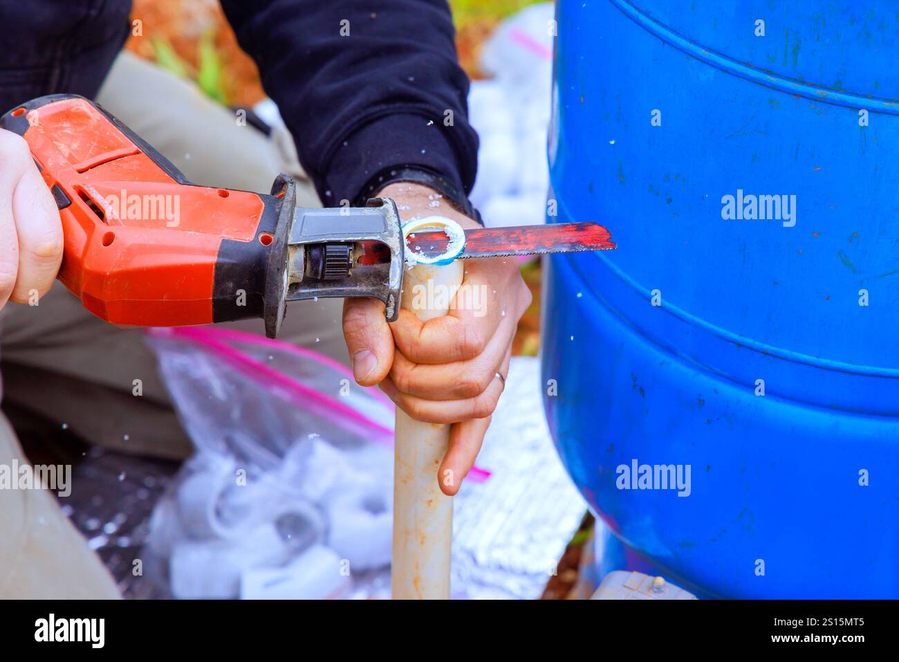 Contractor uses power hand saw to cut pipe for constructing water ...