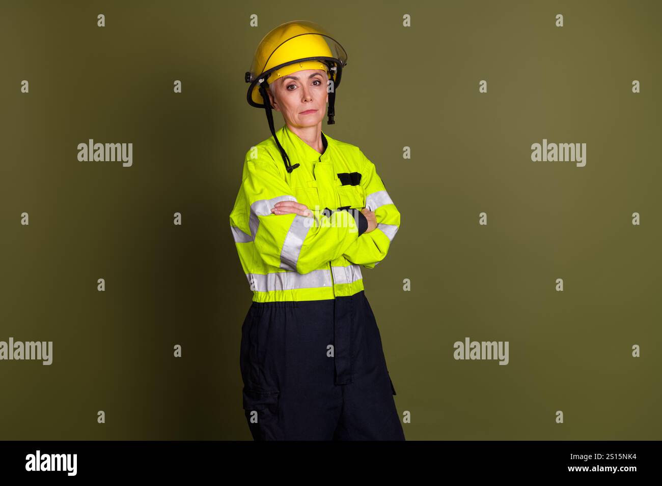 Confident female professional in safety gear stands with arms crossed ...