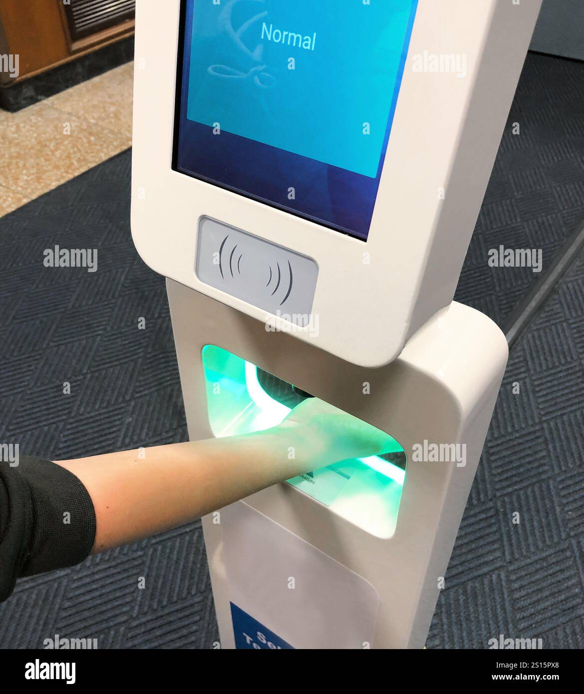 A hand is under a hand wrist temperature check inside a school building ...