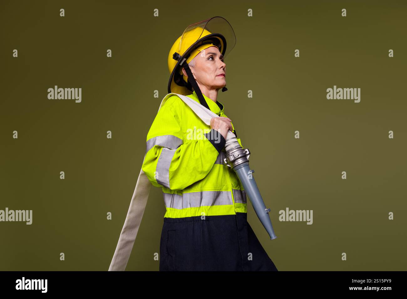 Mature female firefighter in a reflective uniform and helmet holding a ...