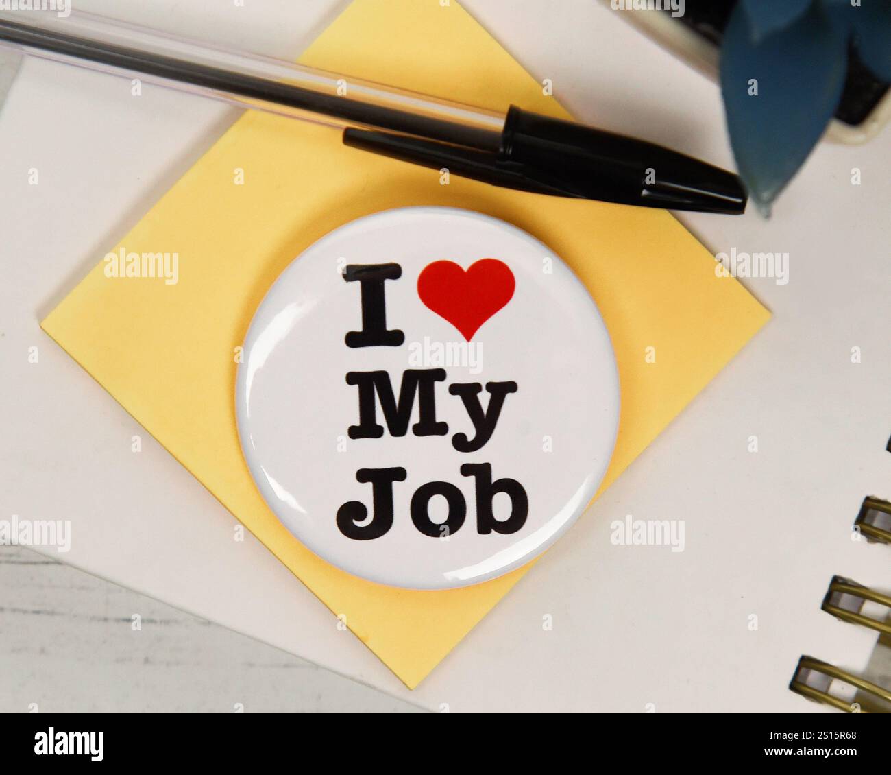 A button is on top of an office desk with a pen that reads I love my ...
