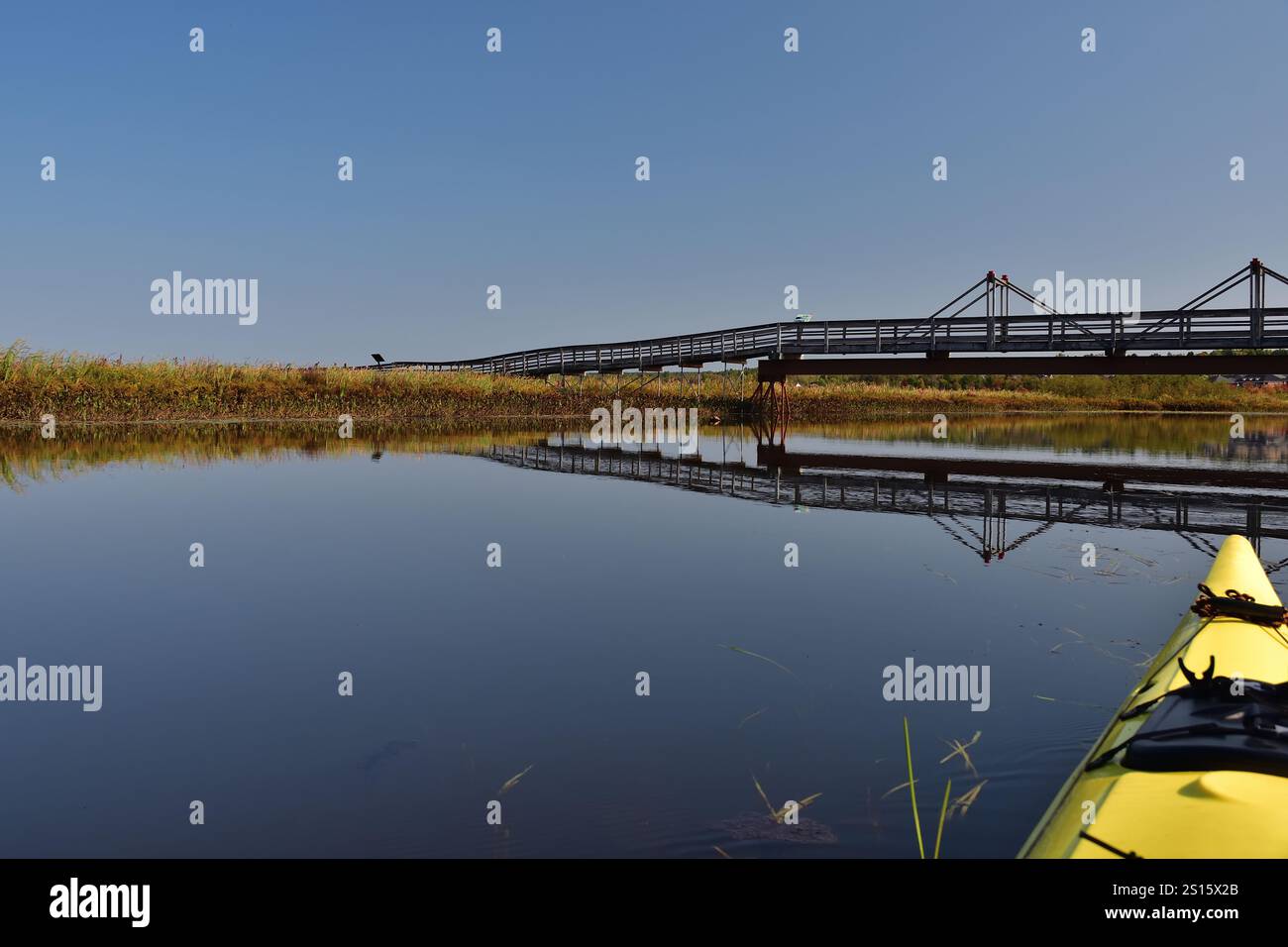 Yellow kayak on mirror like lake. Pedestrian bridge over body of water ...