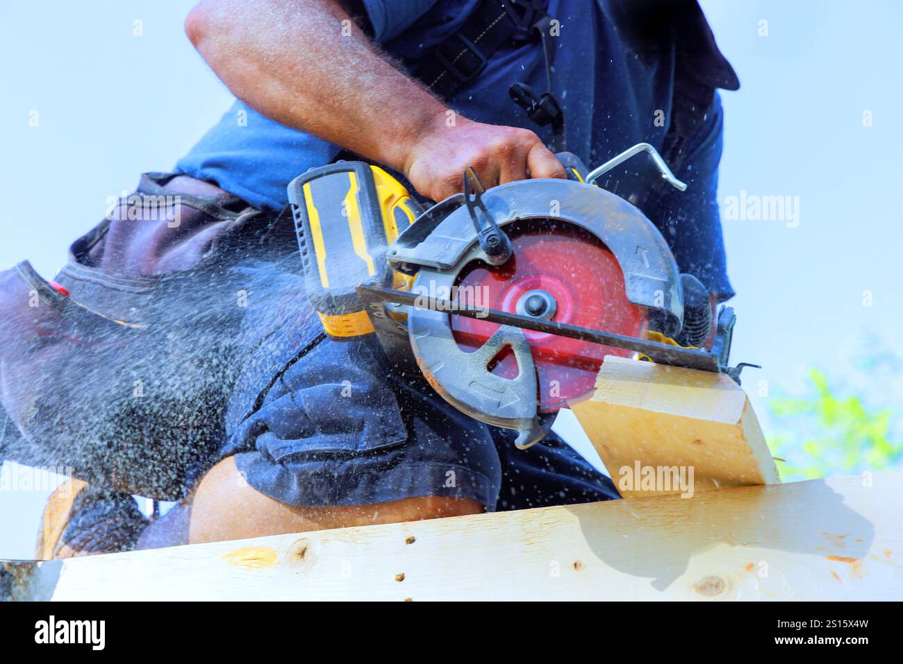 Carpenter cuts wooden frame beams with circular saw while balancing on ...