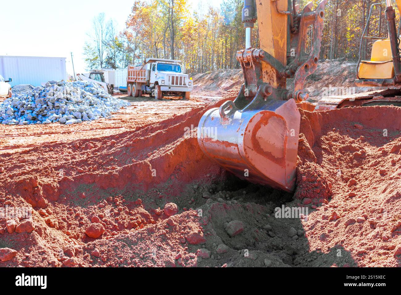 Heavy machinery works to dig into red earth at construction site ...