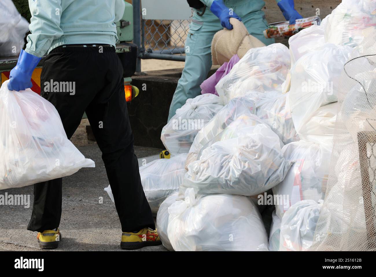 KAGAWA, JAPAN -DECEMBER 30, 2024: Garbage collection workers use truck ...