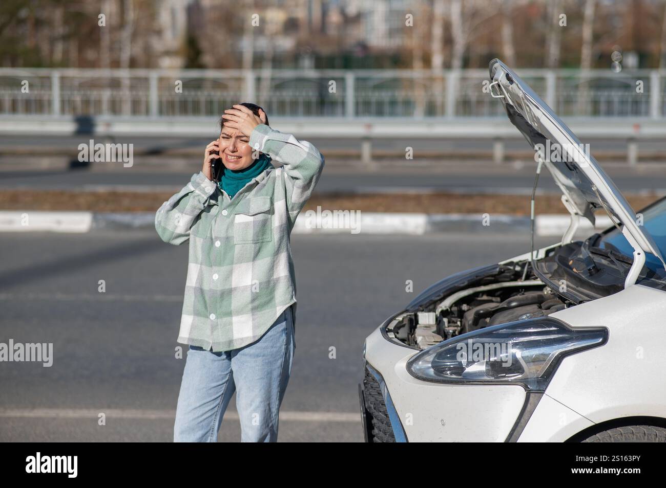 Caucasian woman cries and calls on the phone standing near the car with ...